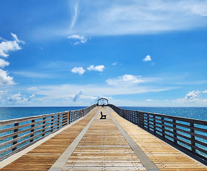 The pier stretches toward infinity, where wooden planks meet endless horizon. A pathway to contemplation with the Atlantic's blue embrace.
