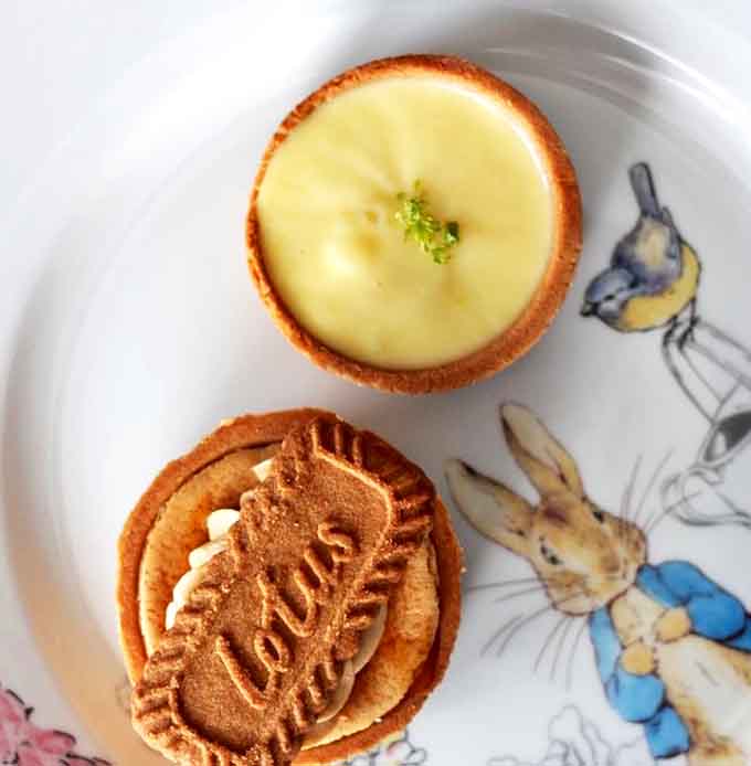 Sunshine on a plate: The bright lemon tart glows alongside a Biscoff creation that transforms a humble cookie into a sophisticated dessert experience.