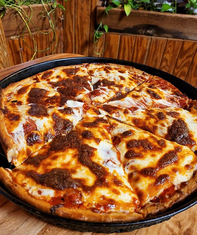 The signature "Pizza in a Pan" emerges golden and glorious, with that perfect cheese-pull that food photographers dream about.