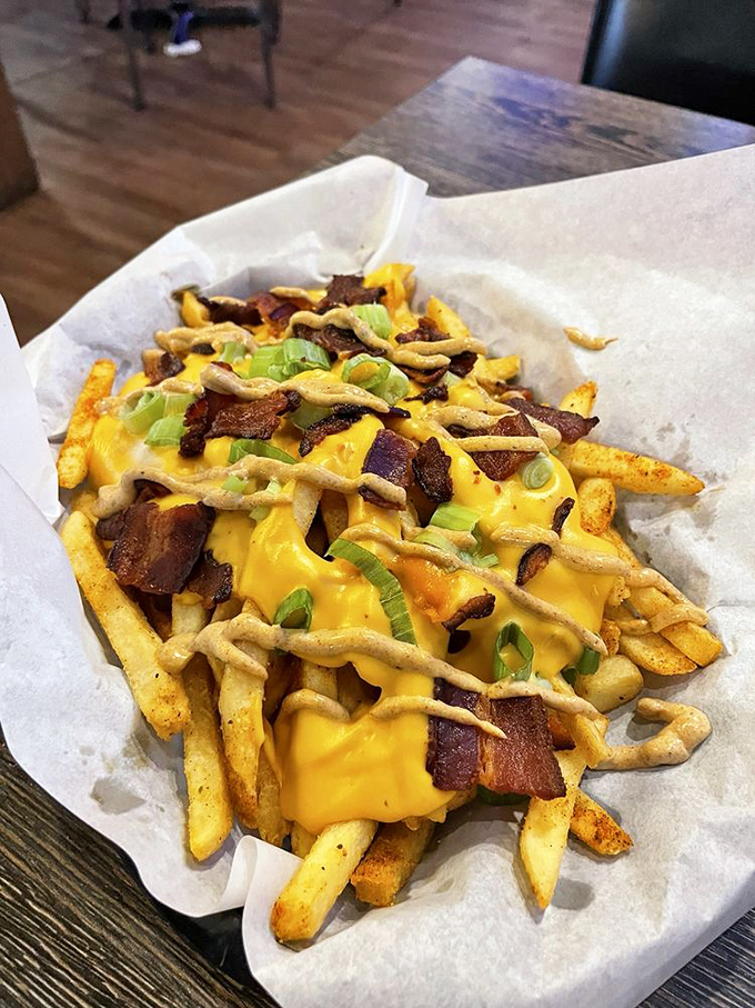 French fries living their best life under a blanket of melted cheese, bacon bits, and green onions. Diet? What diet?