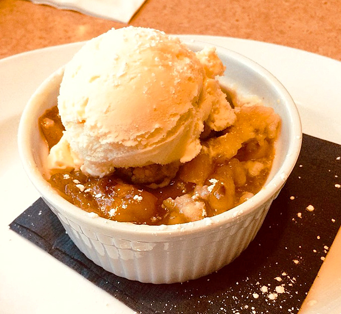 Summer in a ramekin: warm peach cobbler crowned with melting vanilla ice cream &ndash; the kind of dessert that makes you forget your table manners.