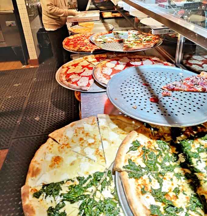 A pizza artist at work, serving slices of happiness to eager customers &ndash; the dollar-covered walls tell stories of visitors from around the world.