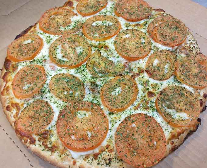 Tomato slices arranged like edible art on a bed of pesto prove that sometimes simple combinations create the most memorable flavors.