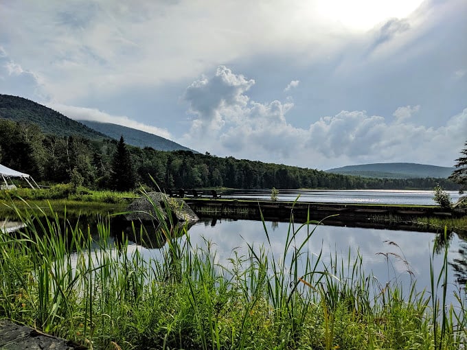 Storm clouds paint drama across Noyes Pond while mountain silhouettes stand guard like faithful sentinels.