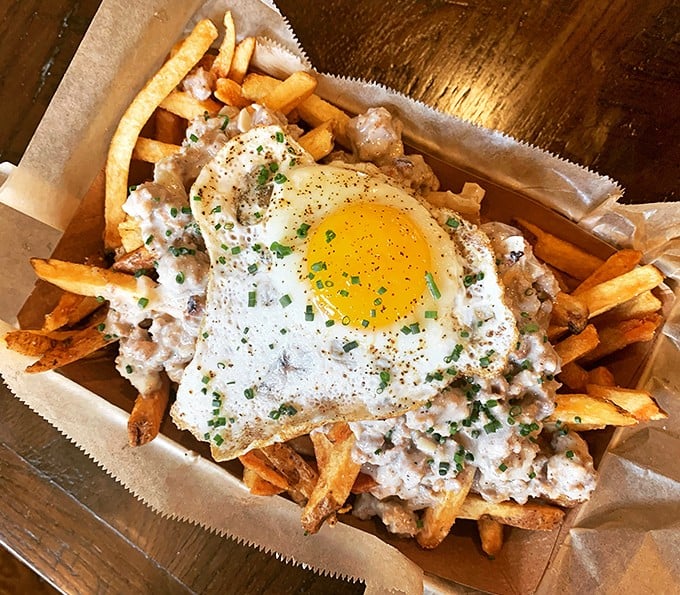 Crispy fries swimming in savory gravy, crowned with a perfect sunny-side egg &ndash; comfort food elevated to an art form.
