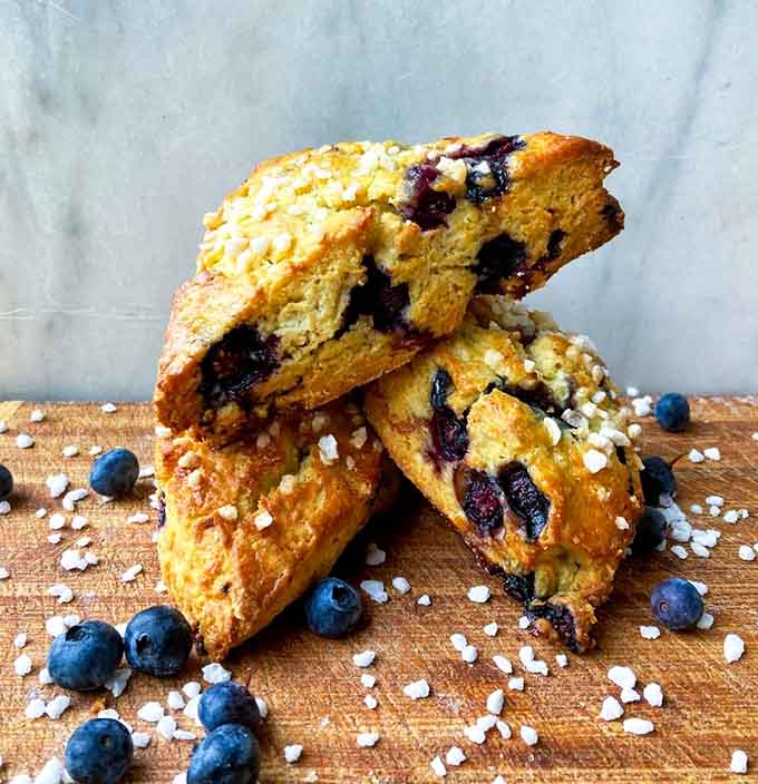 Blueberry scones stacked like edible architecture, studded with fruit and topped with oats that add the perfect crunch to each bite.