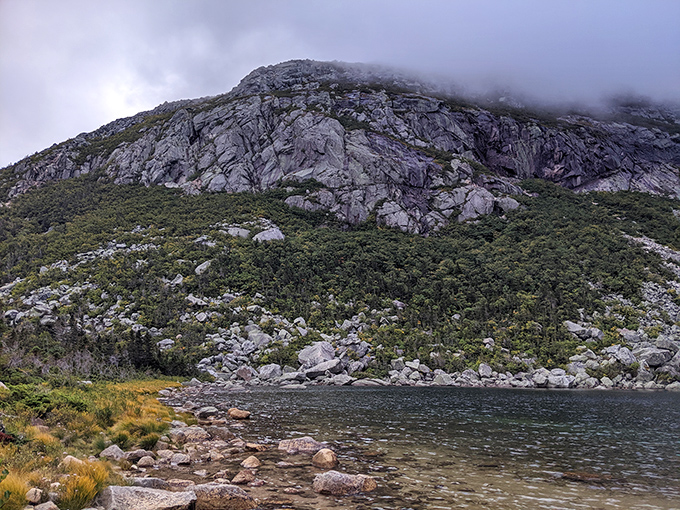 Granite walls that humble: The sheer face of Katahdin rises dramatically from Chimney Pond's shore, a testament to glacial power.