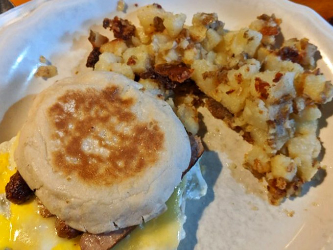 A warm sausage breakfast sandwich sits beside crispy home fries, making a cozy and satisfying morning meal.