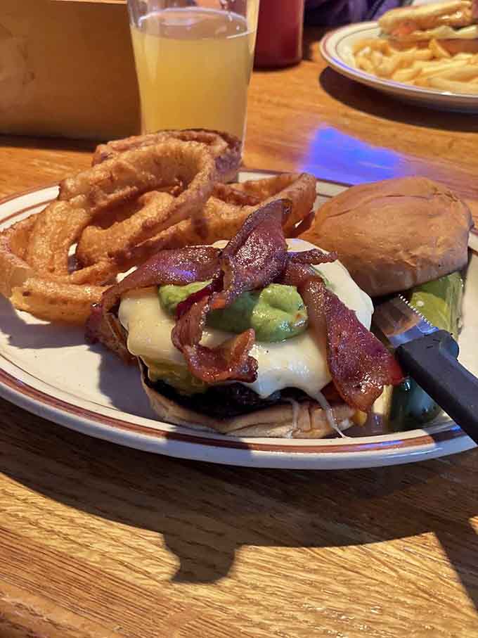 This towering burger loaded with bacon, cheese, and guacamole, paired with crispy onion rings, is basically a edible work of art.