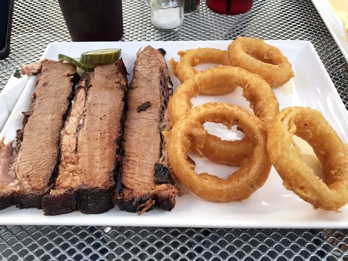 Brisket so tender it barely needs chewing, paired with onion rings that provide the perfect crunchy counterpoint to all that smoky goodness.