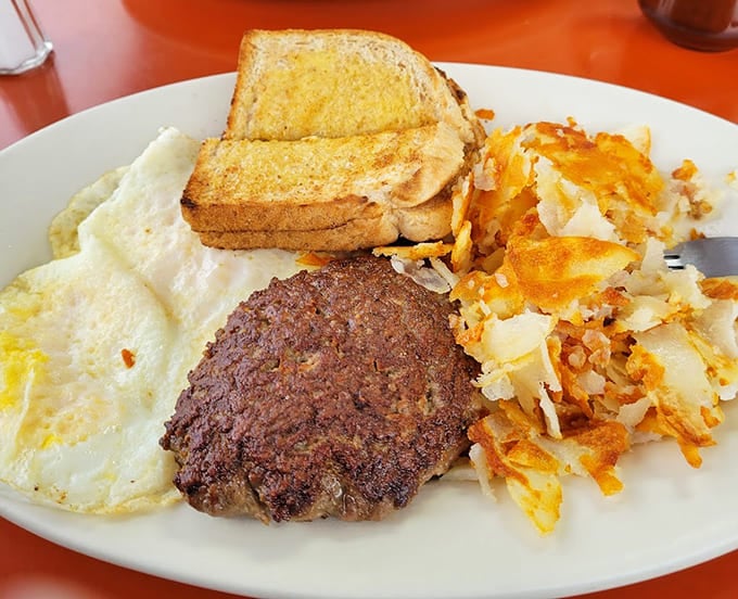 The breakfast platter showcases everything great about American diner food, from perfectly fried eggs to that impressive hamburger steak centerpiece.