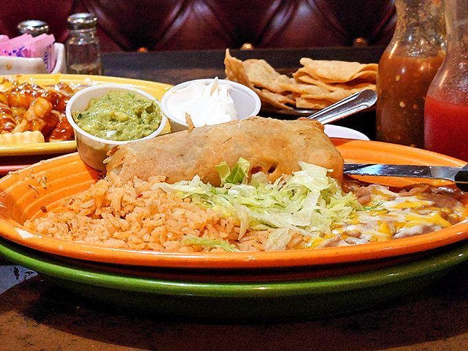 Classic combo perfection: a tender enchilada and crispy taco sharing plate space with Spanish rice and refried beans.