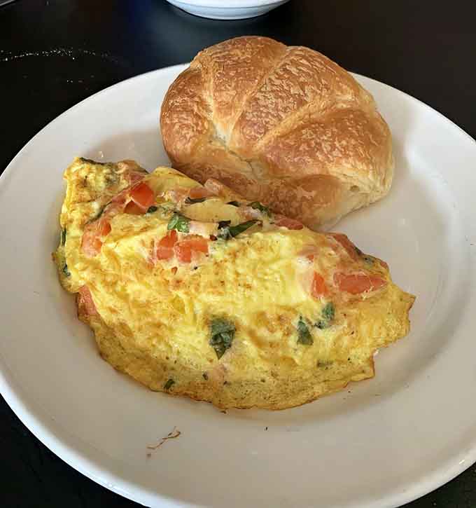 That omelet looks fluffy enough to use as a pillow, paired with a croissant that's practically begging to be devoured.