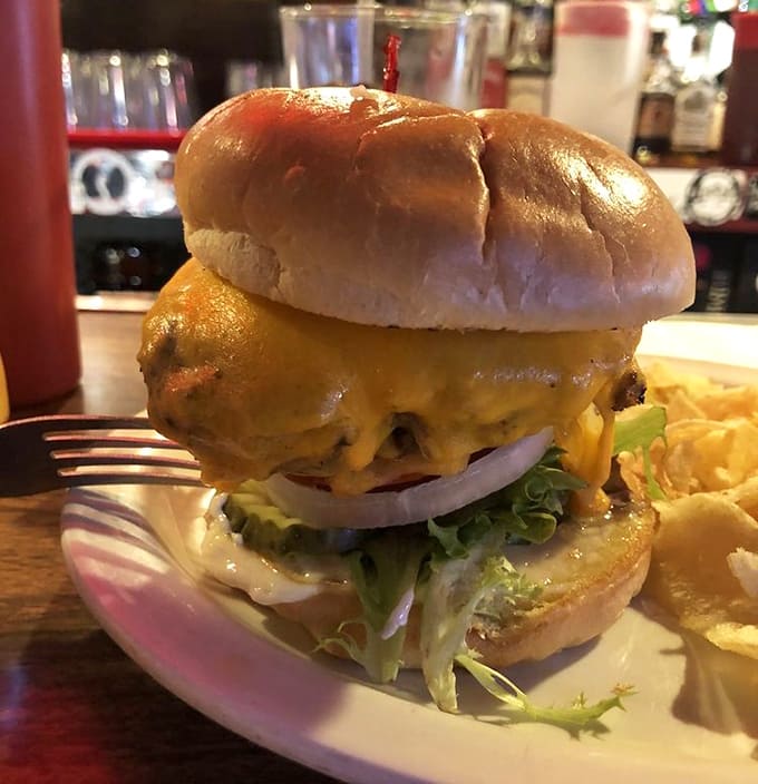 This burger towers like a skyscraper, making you wonder if structural engineering was involved in its creation and consumption strategy.