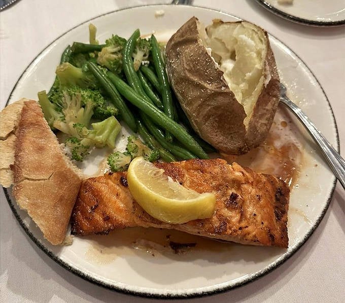 The salmon arrives perfectly cooked, flaking at the touch of a fork, accompanied by seasonal vegetables that complement its delicate flavor.