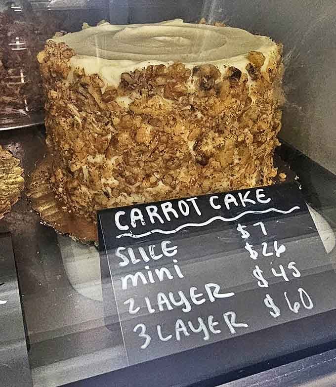 A magnificent carrot cake stands tall and proud, its sides armored with chopped walnuts, ready to become the centerpiece of someone's celebration.