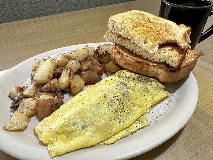 The breakfast trinity: golden-yellow eggs, crispy-edged home fries, and toast waiting for its butter destiny. Simple perfection on a plate.