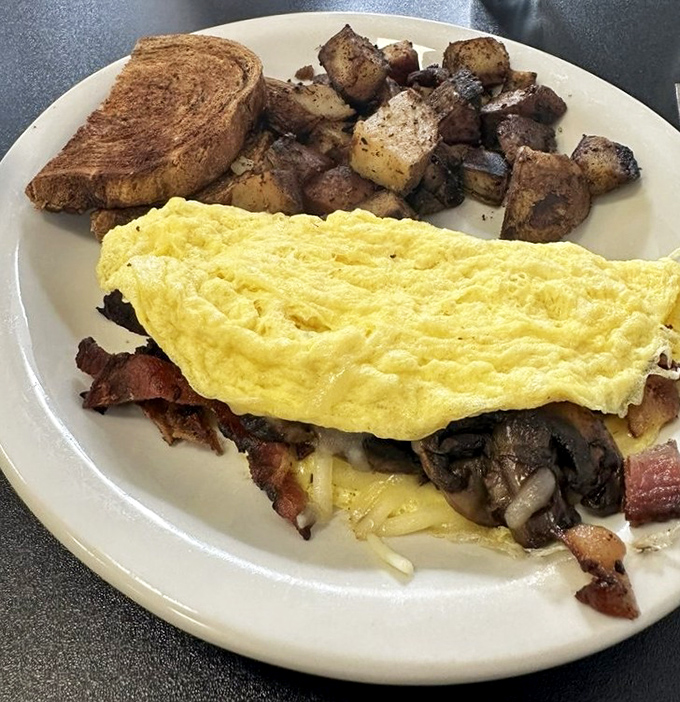 The omelet of champions – a perfect yellow envelope stuffed with savory treasures, accompanied by home fries that deserve their own fan club.