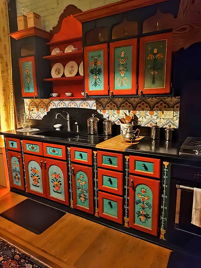 Louise's kitchen bursts with personality, its hand-painted cabinets showcasing vibrant colors that would make even the most serious chef smile.