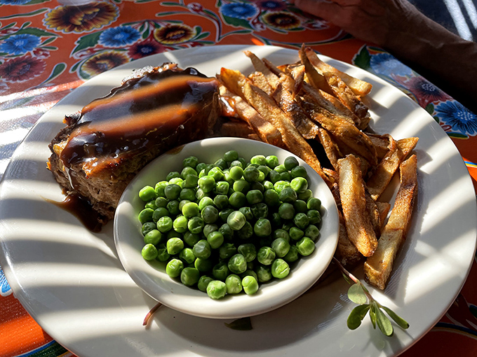 Comfort food trifecta: meatloaf, hand-cut fries, and those bright green peas that somehow taste better in a diner than anywhere else.