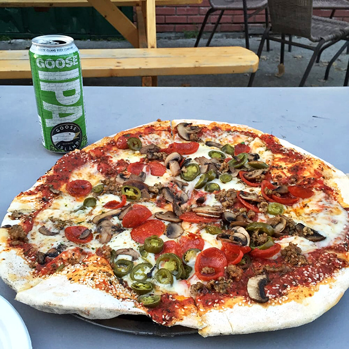 Wood-fired pizza perfection: a crisp, blistered crust topped with pepperoni, mushrooms, and jalape&ntilde;os, with a Goose Island IPA standing guard.