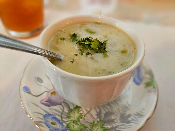 A steaming cup of homemade soup arrives in a delicate teacup with saucer, proving comfort food can indeed be elegant.