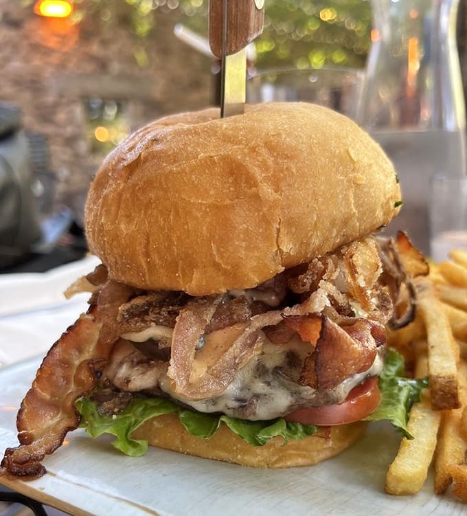 This burger towers like a delicious skyscraper, requiring both hands and possibly an engineering degree to eat properly.