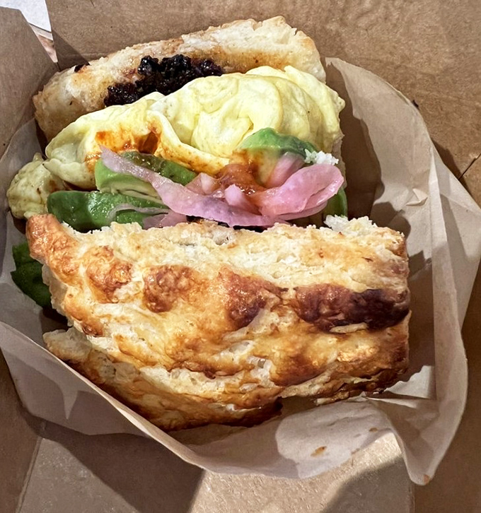 Breakfast architecture at its finest: a perfectly constructed sandwich where every ingredient plays its part, all embraced by that heavenly, flaky biscuit exterior.