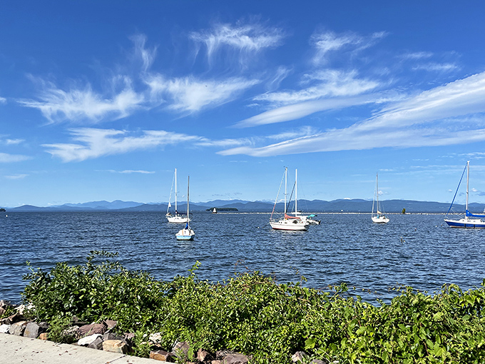The calm lake waters host dozens of anchored sailboats, creating a postcard-perfect scene that changes with each passing cloud.