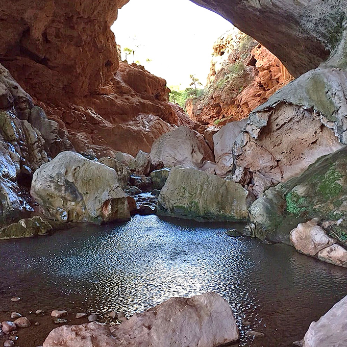 Crystal pools gather beneath the arch, nature's mirrors reflecting millions of years of geological craftsmanship in perfect stillness.