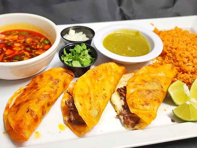 Birria tacos get the gourmet treatment with melted cheese and consomm&eacute; for dipping, elevating this trendy dish to new heights.