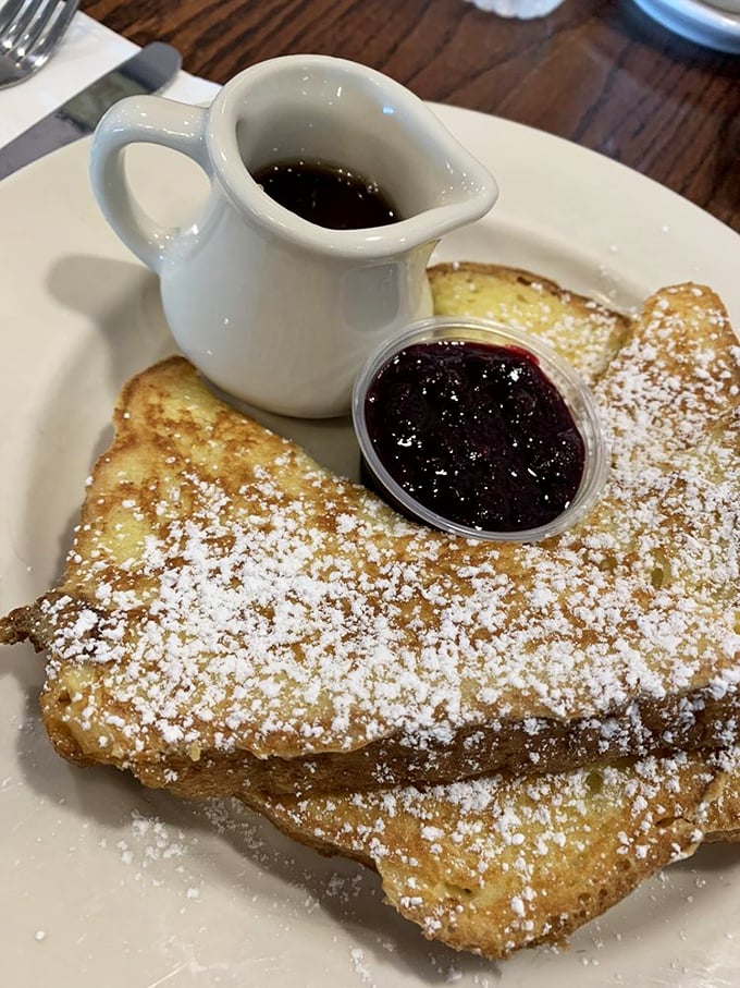 Golden-brown French toast dusted with powdered sugar, accompanied by berry jam that means serious business.