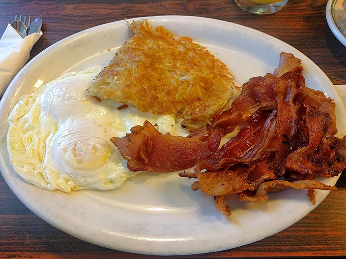 The breakfast trinity: eggs with just-right yolks, bacon with the perfect crisp-to-chew ratio, and those legendary hash browns that steal the show.