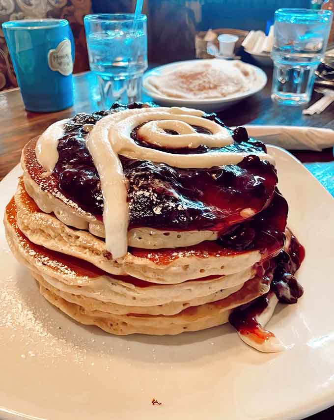 Blueberry pancakes stacked high with berry compote and cream swirls look almost too pretty to eat.