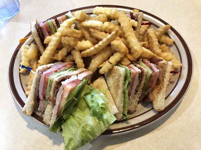 This club sandwich towers with layers of turkey, ham, bacon, and fresh vegetables, served with fries that stay crispy to the last bite.