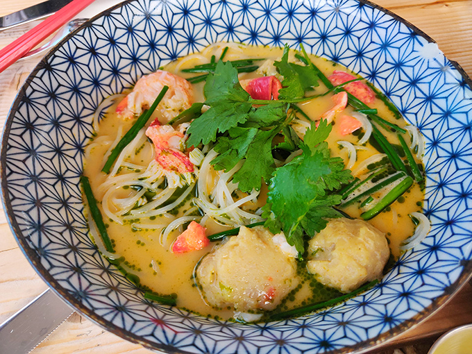 Sunshine in a bowl &ndash; creamy coconut curry embraces rice noodles and sweet lobster chunks while fresh herbs add bright pops of flavor.