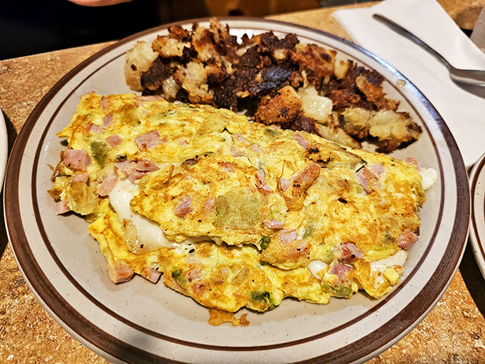 This isn't just an omelet – it's a masterpiece of morning cuisine, stuffed with ham and veggies, with crispy potatoes standing guard.
