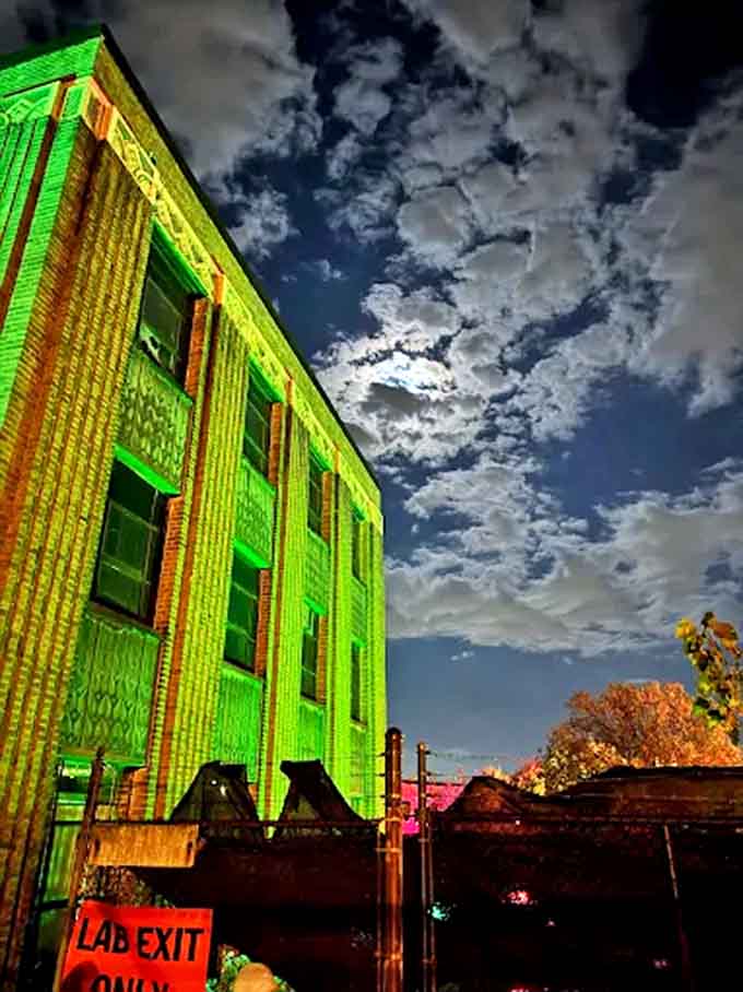 Eerie green lighting bathes the building at night, creating an otherworldly glow against the cloudy sky that screams "turn back now!"