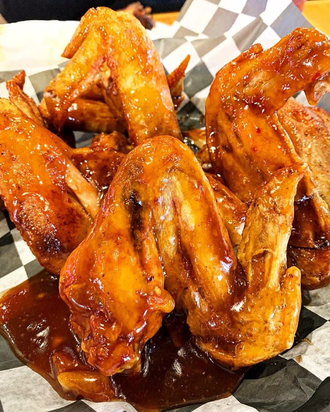 Those plum-glazed wings glisten like edible jewels, offering a sweet-tangy flavor adventure that'll have you licking your fingers shamelessly.