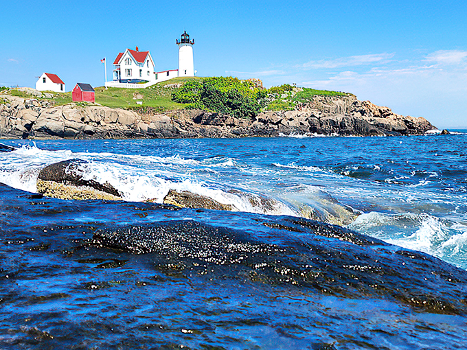 The lighthouse watches over churning waters and weather-worn rocks, a scene straight out of a maritime painter's dreams.