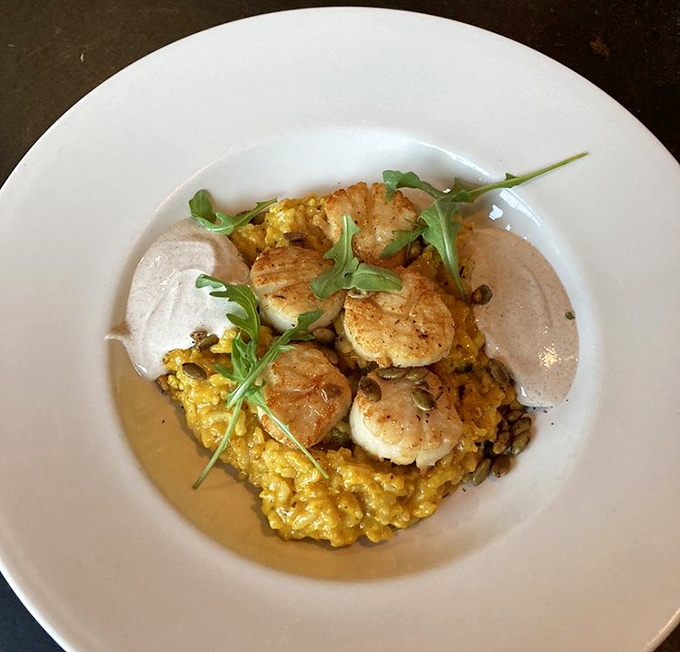 Perfectly seared scallops perch atop a golden throne of saffron risotto, with delicate microgreens adding color and a whisper of freshness.