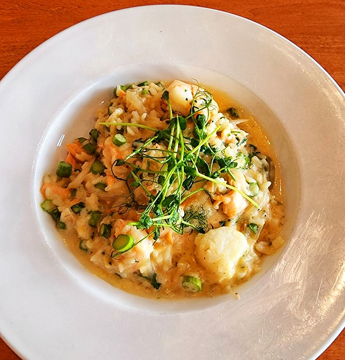 Seafood risotto that whispers "take your time" &ndash; creamy rice cradling tender scallops, shrimp and salmon with fresh herbs.