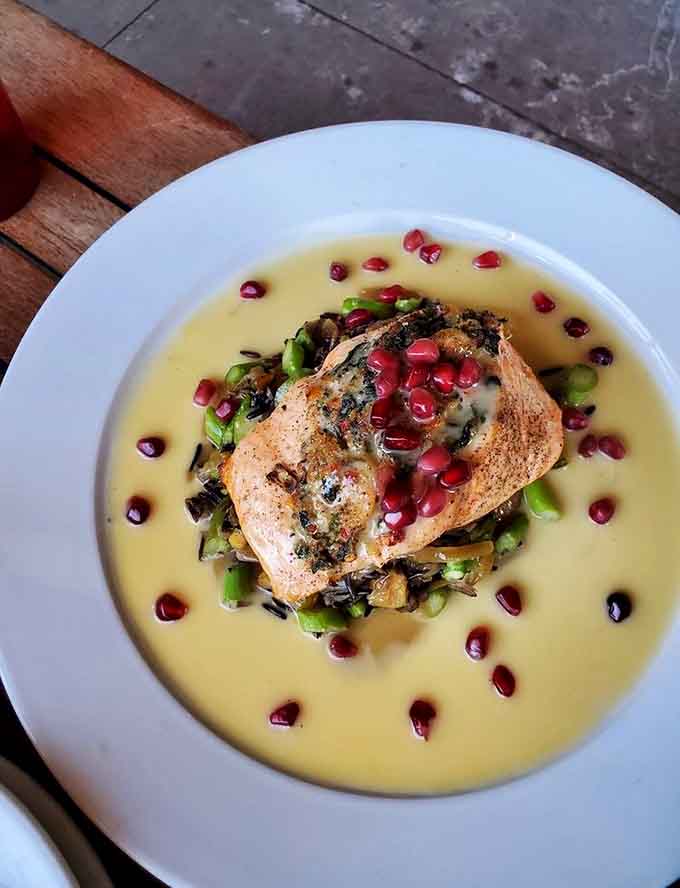 Braised greens add an earthy contrast to the rich salmon, creating a balanced plate that's Instagram-worthy and delicious.