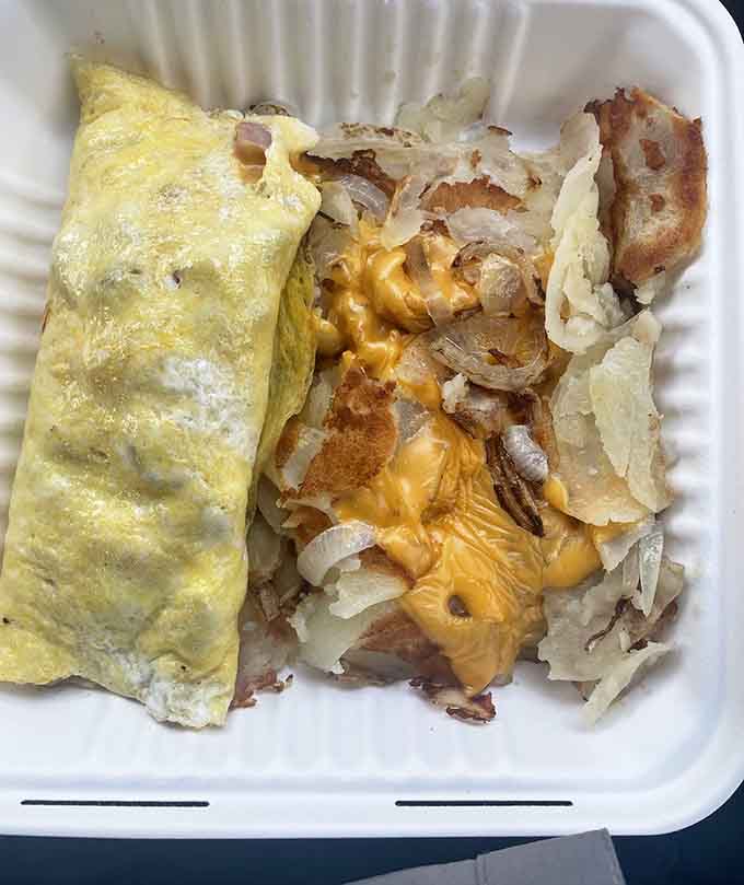 That omelet is stuffed with cheese, onions, and fried potatoes: basically everything good in life folded into egg perfection.