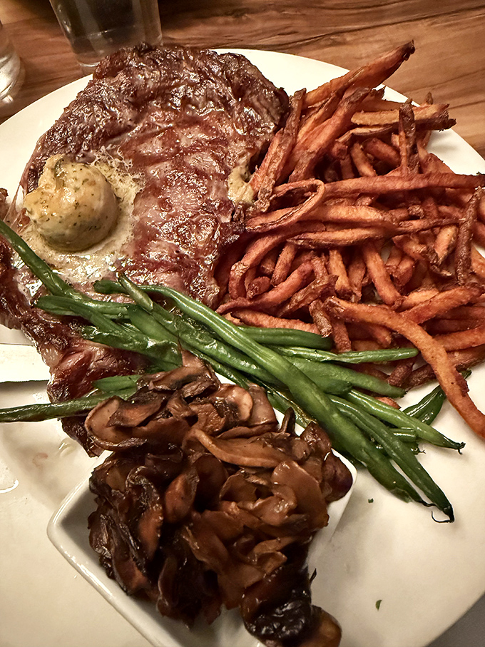 The Ribeye steak arrives with a battalion of crispy fries and mushrooms – a carnivore's dream team on a single plate.