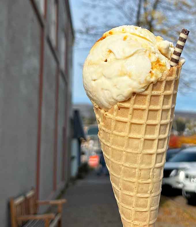 A waffle cone loaded with golden ice cream stands tall like a delicious tower of happiness you can actually eat.