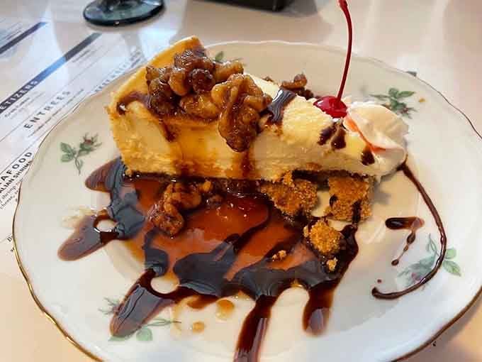 Turtle cheesecake towers above chocolate drizzles like a dessert skyscraper, combining caramel, pecans, and pure indulgent joy.