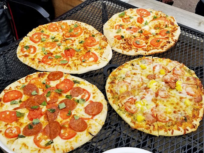 Four different pizzas fresh from the wood-fired oven, each with that perfect char and bubble action that makes pizza lovers weep with joy.