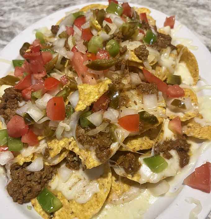 These aren't your average nachos; they're a mountain of chips, meat, cheese, and vegetables that could feed a hungry crowd.