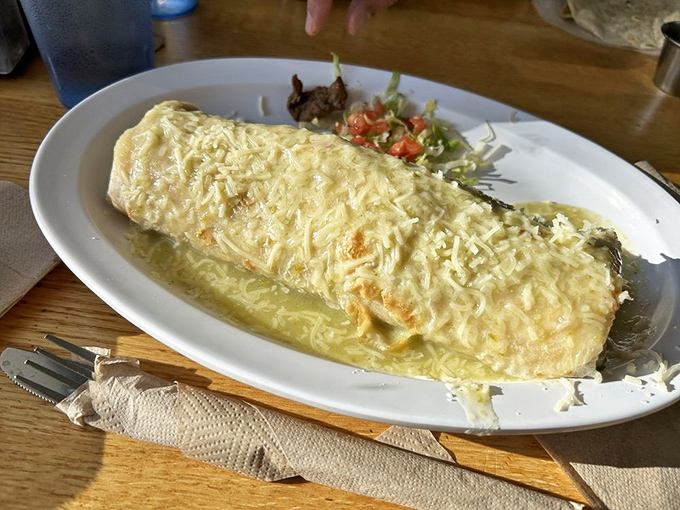 The wet burrito with green chile sauce glistens with promise &ndash; a flavor bomb waiting to detonate on your taste buds.